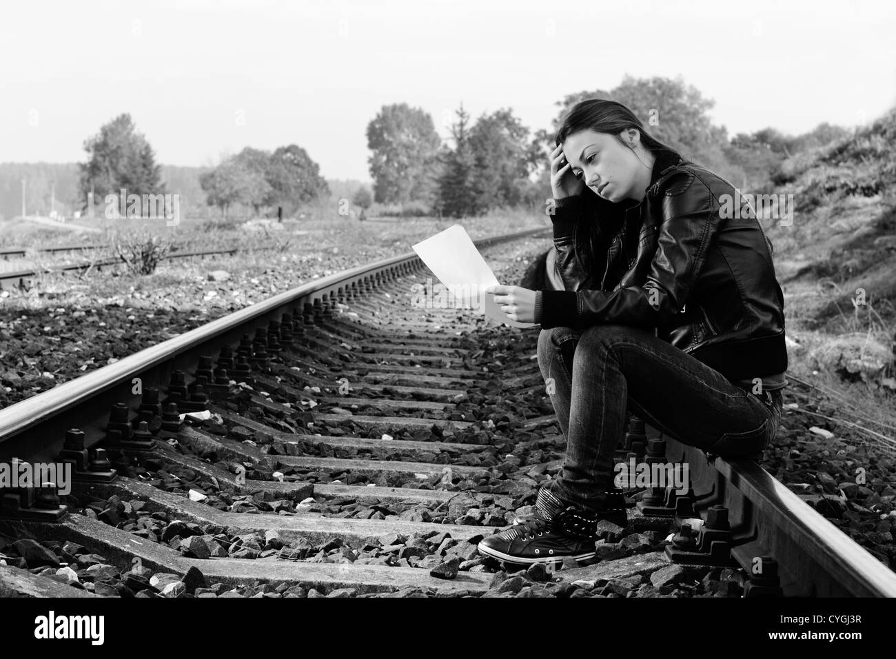 Depressed and lonely teenage girl reading the letter on railroads Stock ...