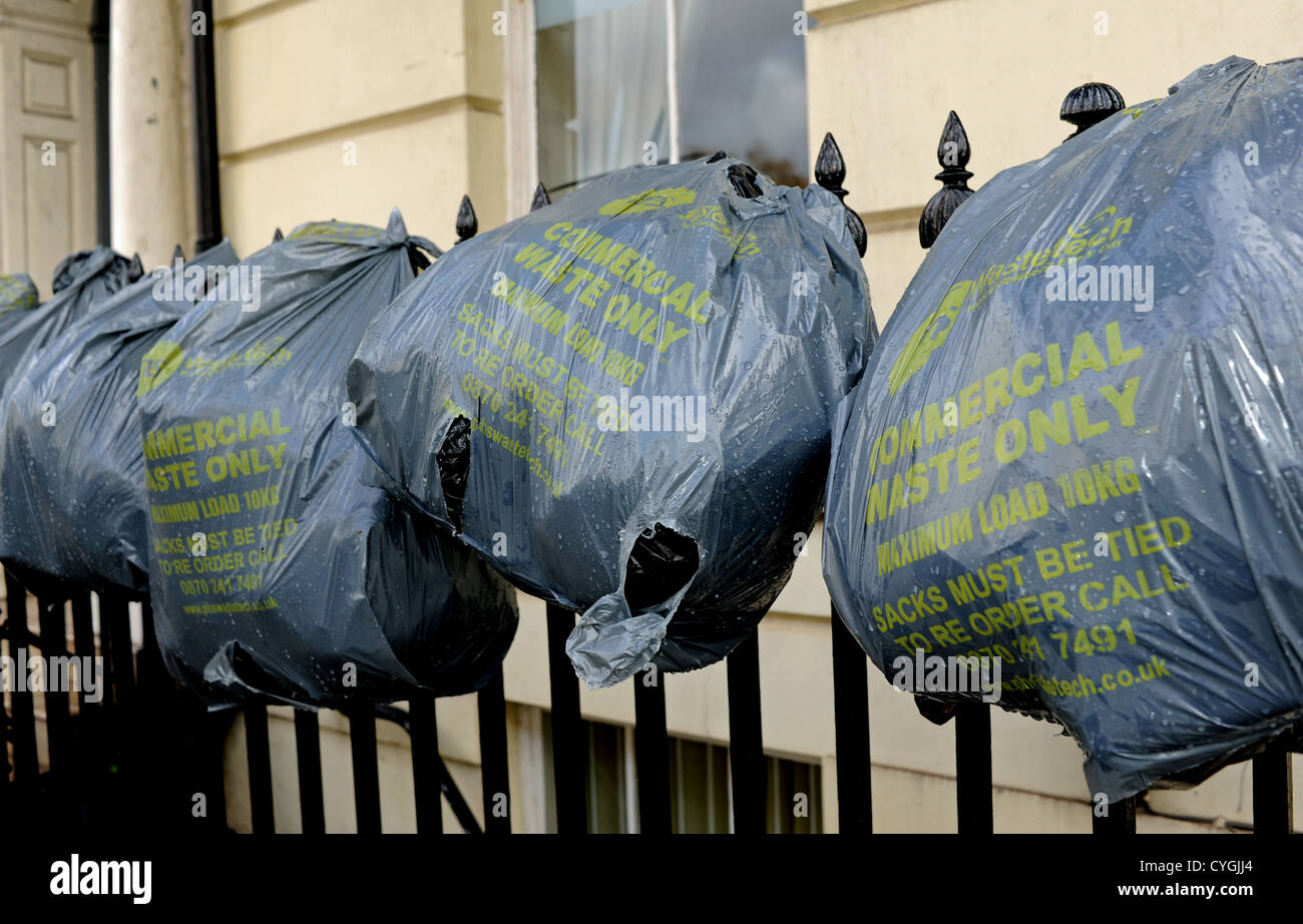 Commercial Waste Only rubbish bags hanging on iron railings fence in ...