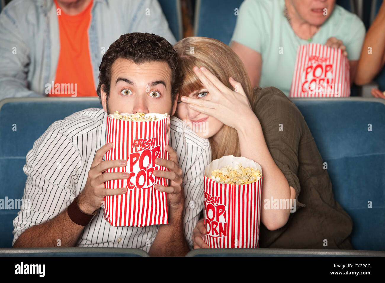 Scared couple hiding behind popcorn bags Stock Photo - Alamy