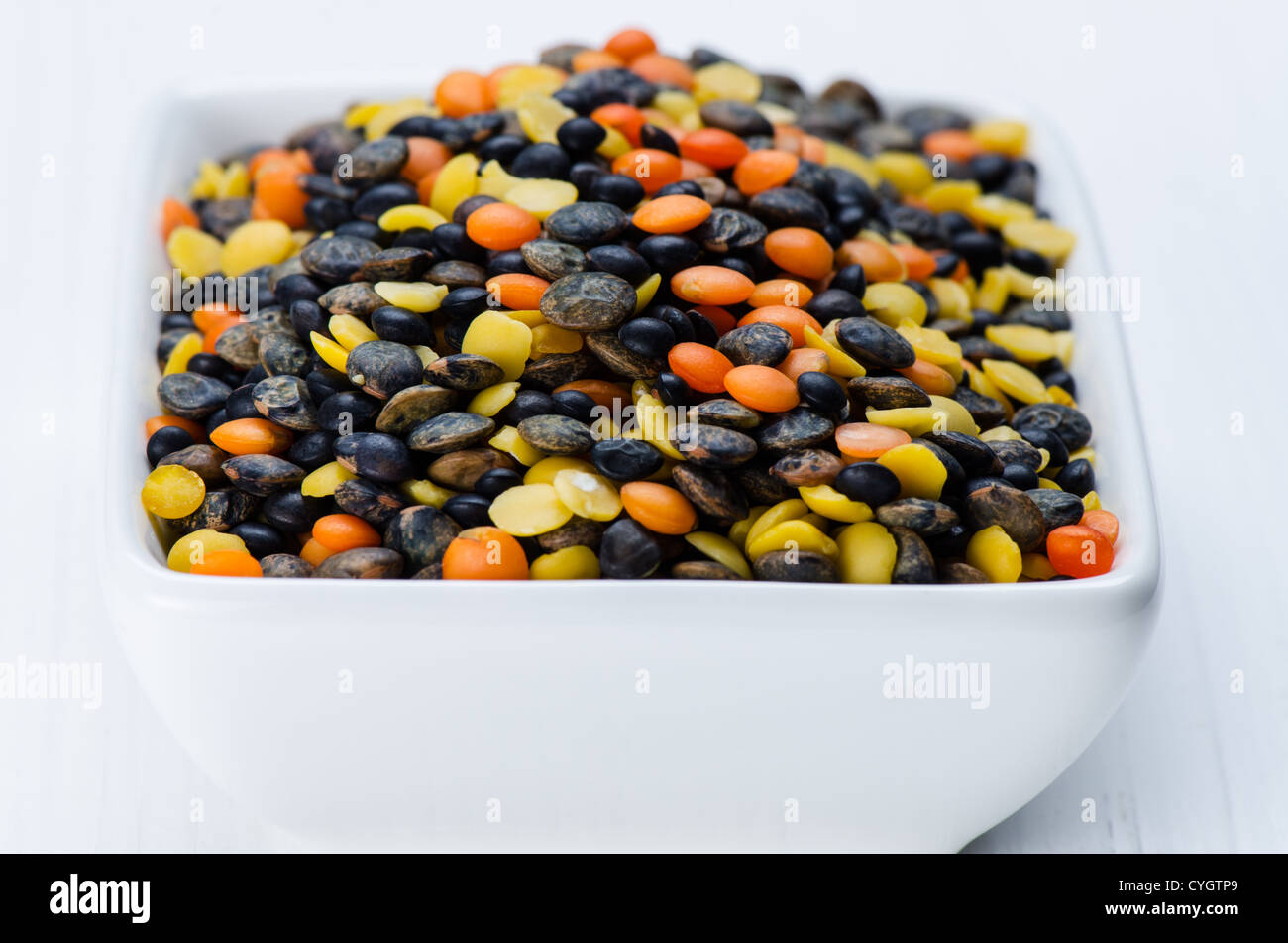 Mix of lentils in a bowl on white wooden table Stock Photo - Alamy