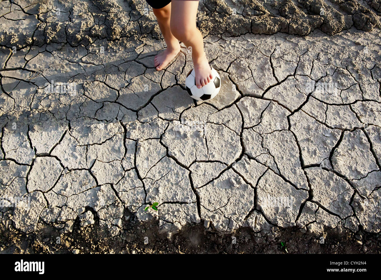 Dry road and barefoot child's legs with football Stock Photo - Alamy