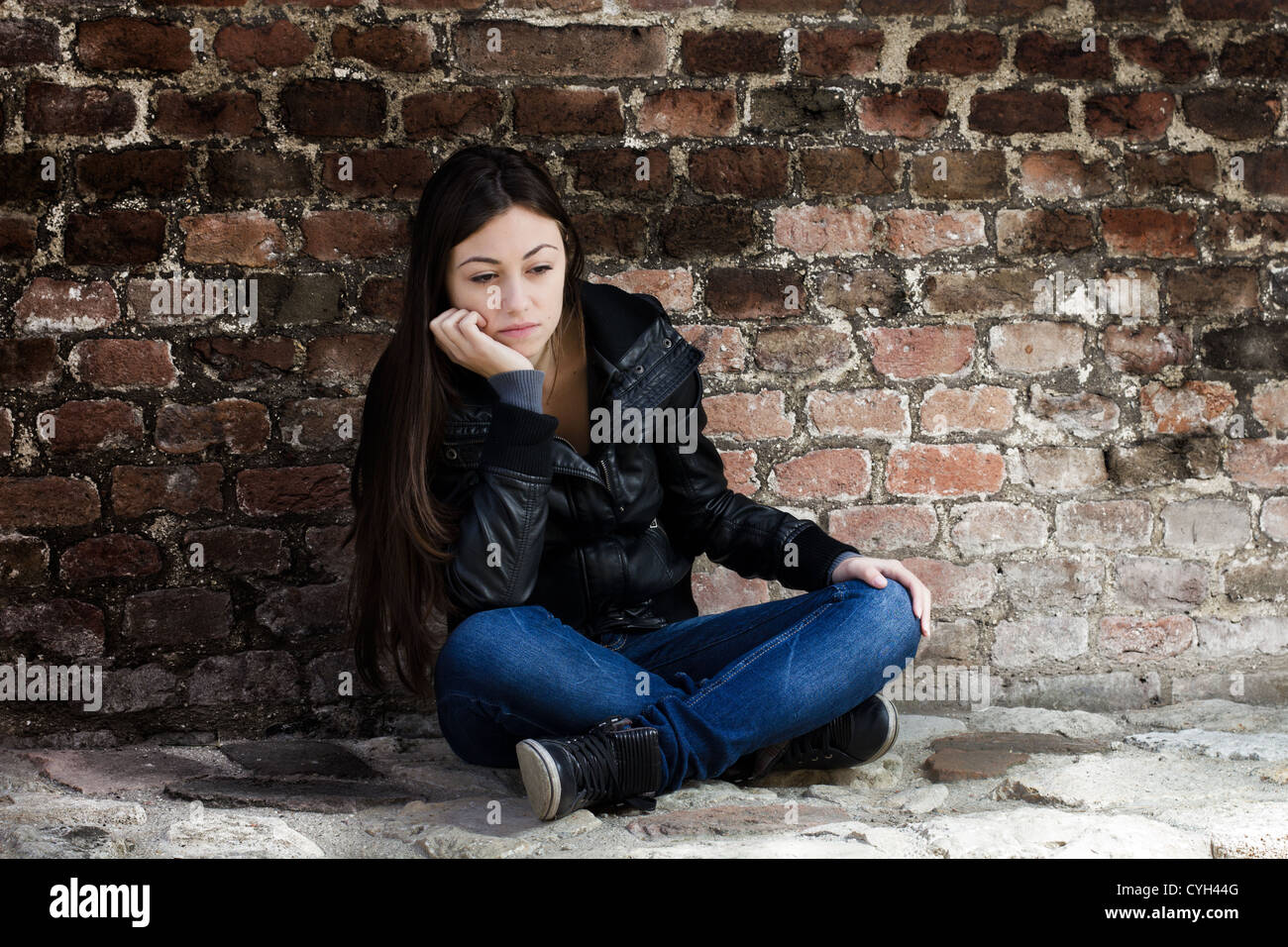 Sad teenage girl, leaning on an old brick wall Stock Photo - Alamy