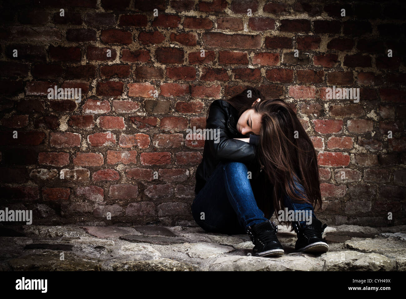 Sad teenage girl, leaning on an old brick wall Stock Photo - Alamy