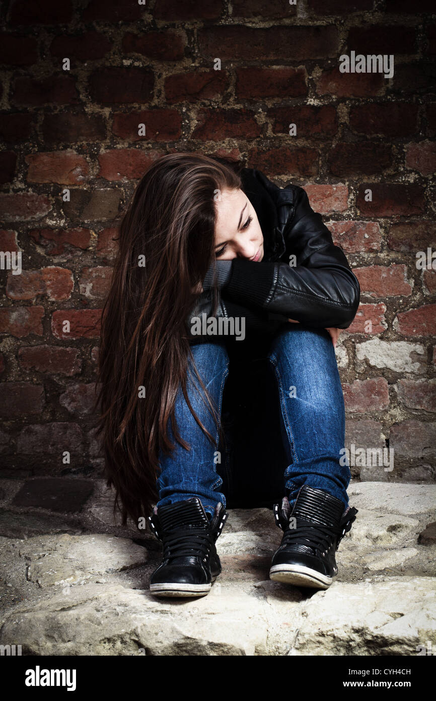 Sad teenage girl, leaning on an old brick wall Stock Photo - Alamy