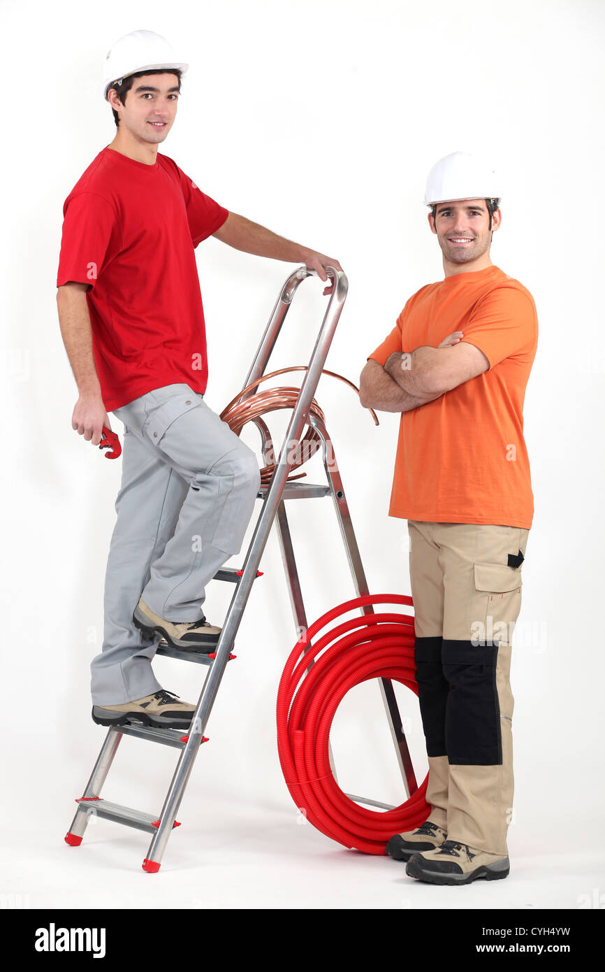 Two plumbers stood with ladder and copper pipe Stock Photo - Alamy