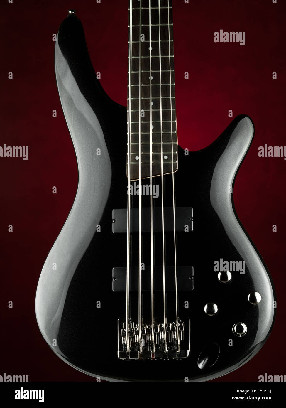 Five string electric bass guitar over red background, for music ...