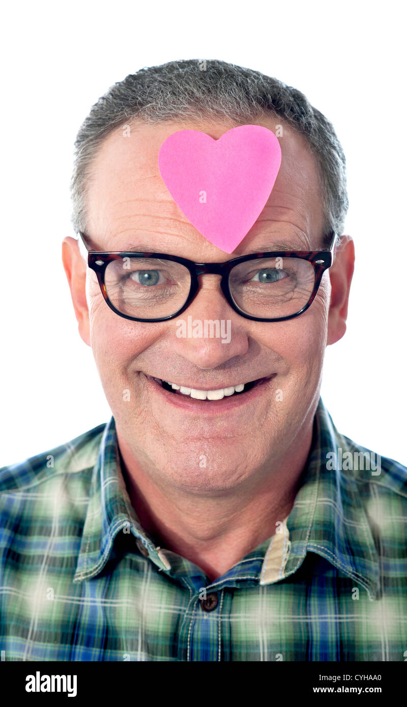 Handsome senior man with paper heart on his forehead. Smiling at camera ...