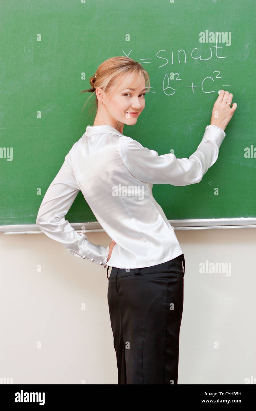 The teacher in the classroom on blackboard background Stock Photo - Alamy
