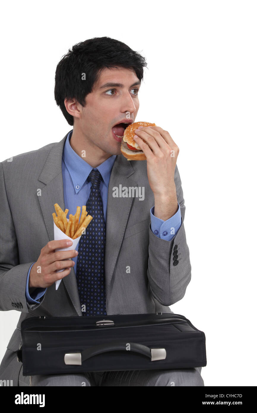 Businessman eating junk food Stock Photo - Alamy