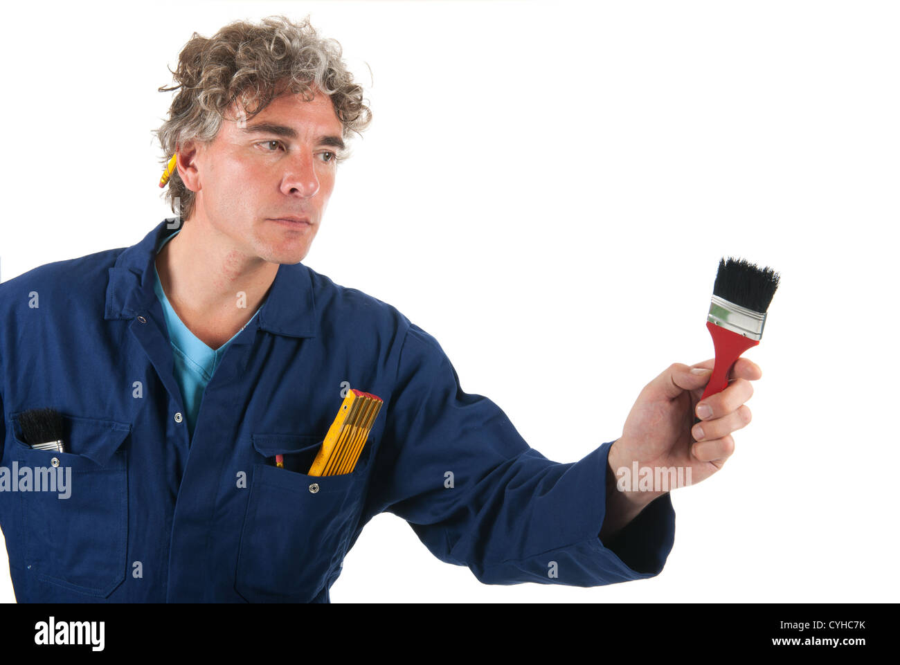 Handsome handyman in blue overall painting with red brush Stock Photo ...
