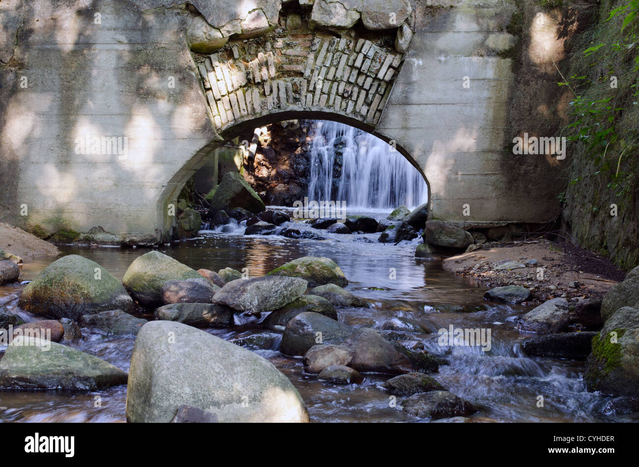 Retro architecture arch in wall and stream flowing from waterfall Stock ...