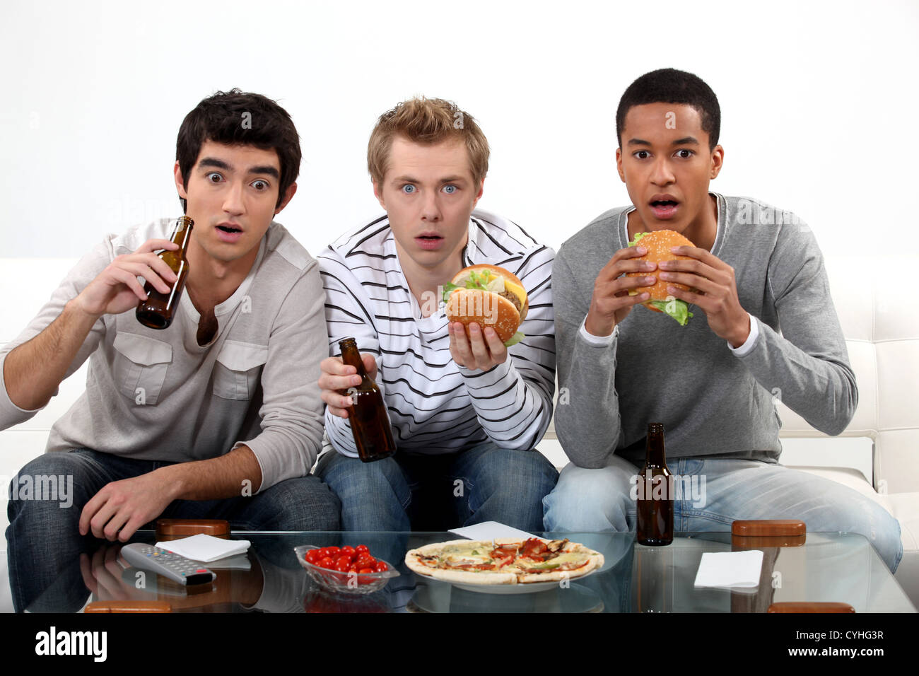 Stunned men watching a horror film Stock Photo - Alamy