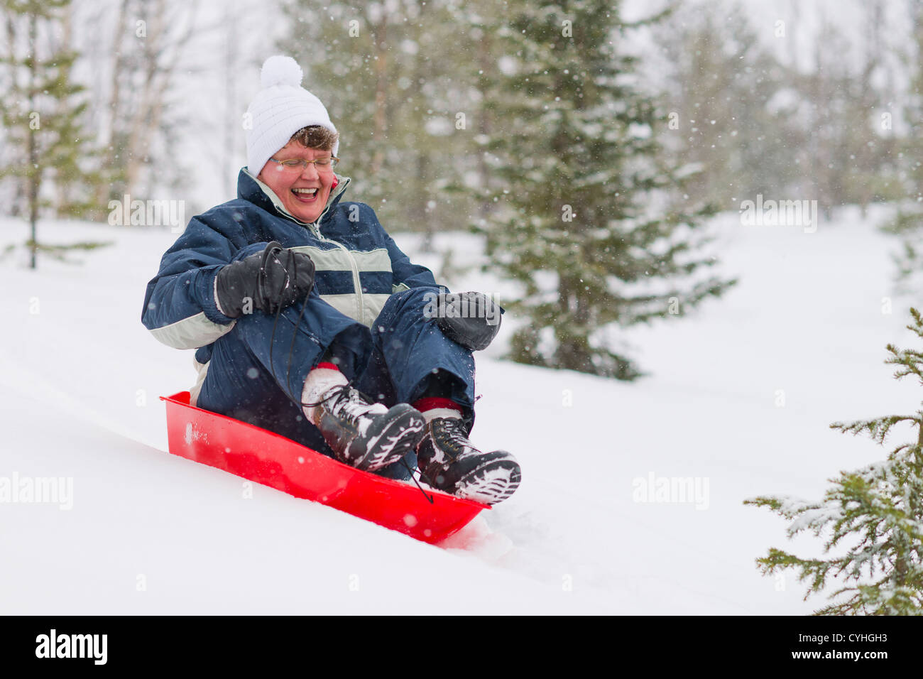 Woman sledding down the hill in the snowfall Stock Photo - Alamy