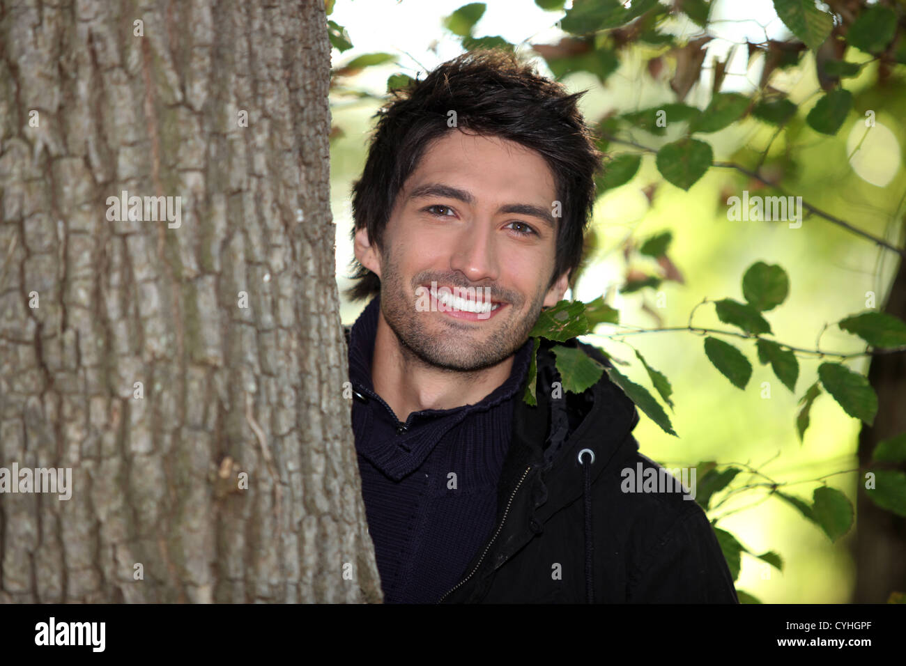 Man behind the tree trunk Stock Photo - Alamy