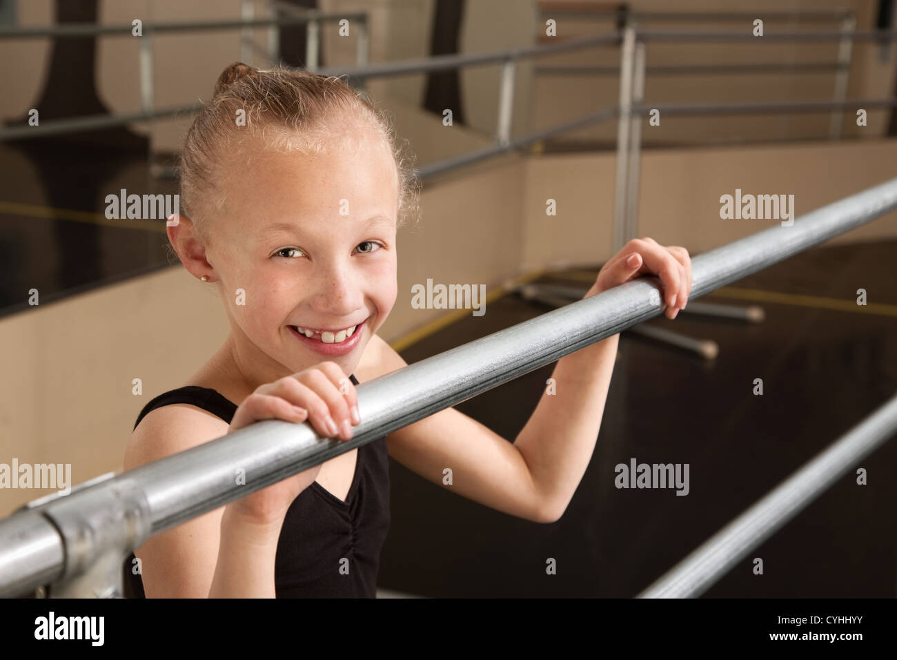 Smiling cute ballet student holds railing in dance studio Stock Photo ...