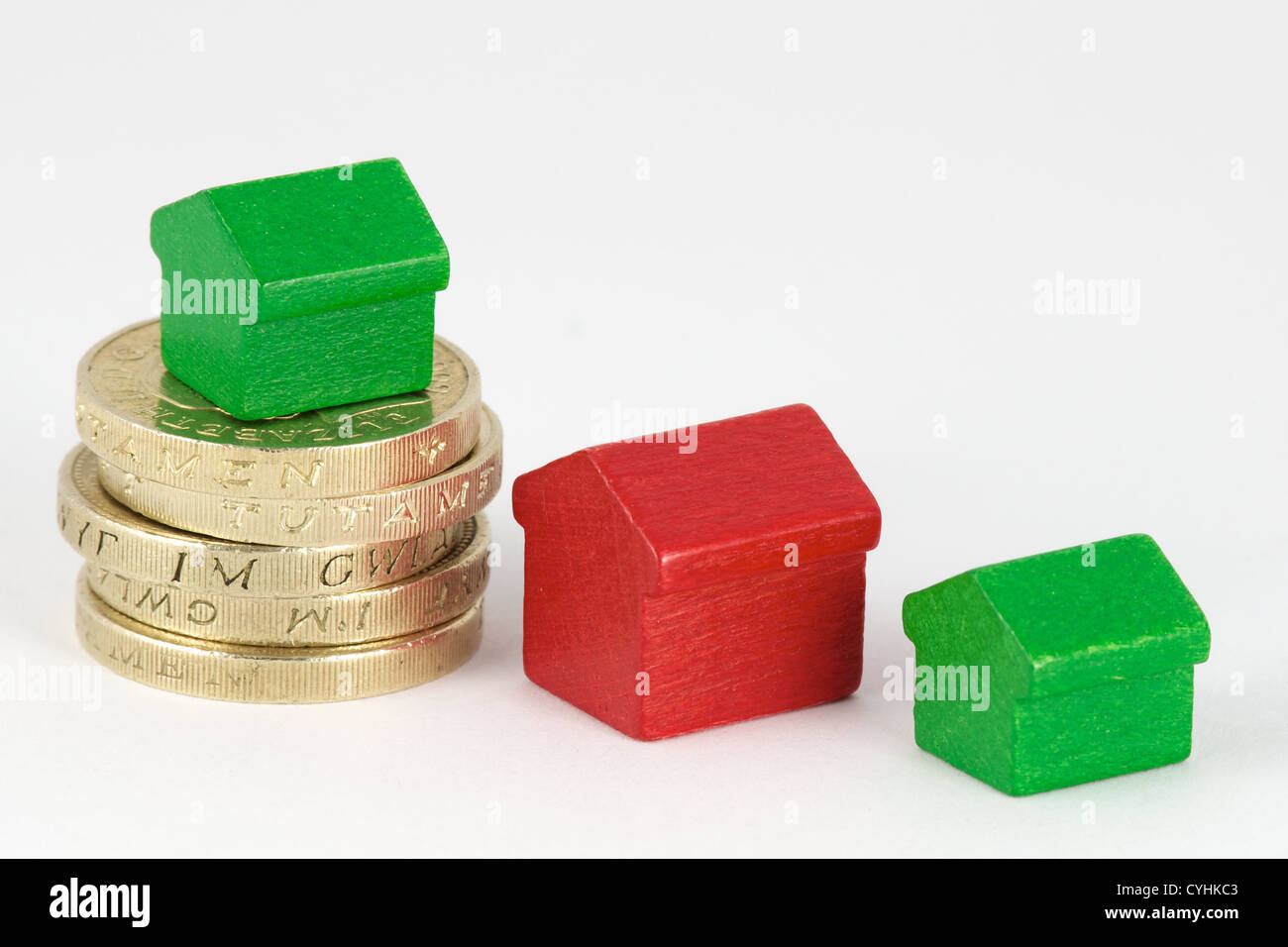 Stack of British pound coins with red and green wooden houses isolated ...