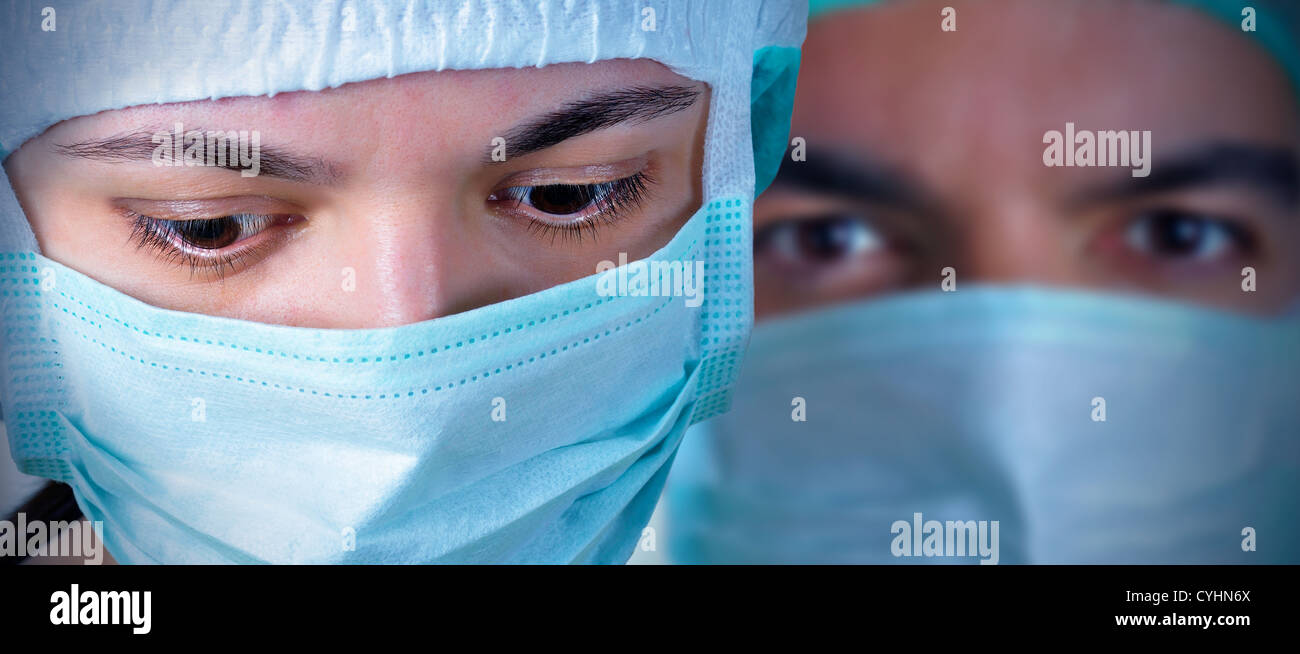 Closeup portrait of two surgeons during a surgery. Blue cast and ...