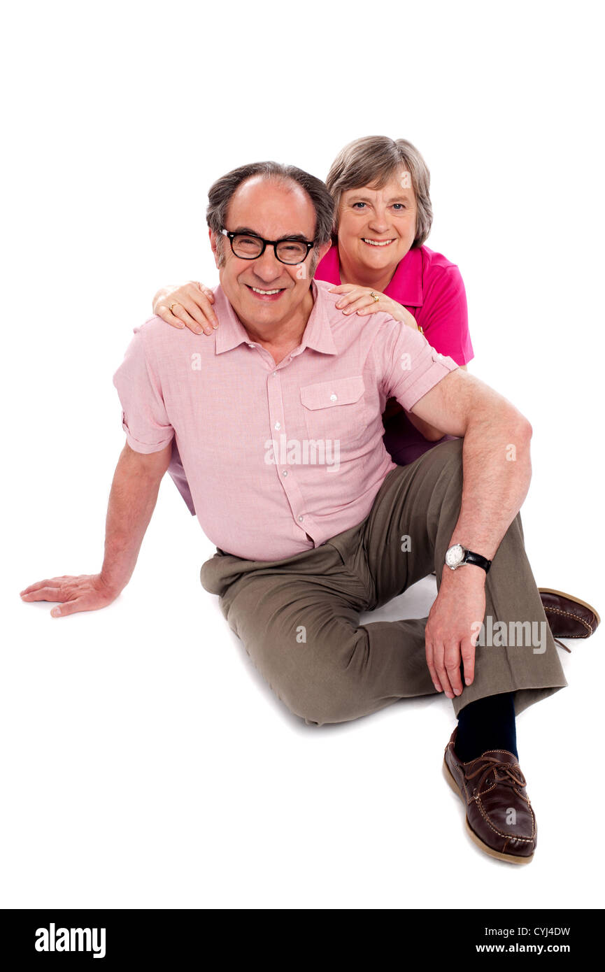 Smiling senior couple seated on floor. Posing against white background ...