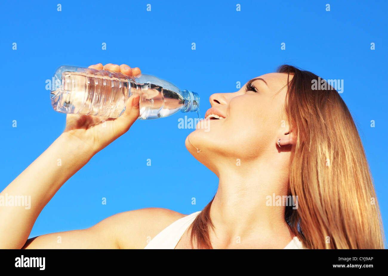 Beautiful female drinking water over blue sky background Stock Photo ...
