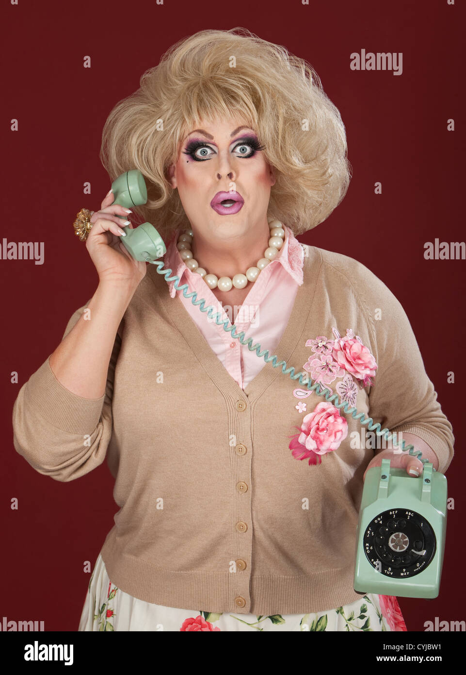 Surprised drag queen holding telephone over maroon background Stock ...