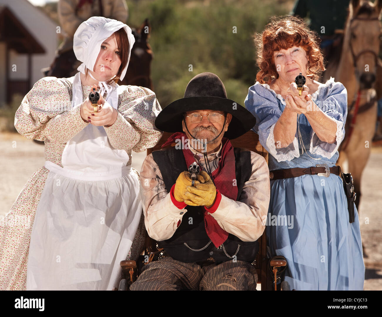Three people with guns out in old American west scene Stock Photo - Alamy