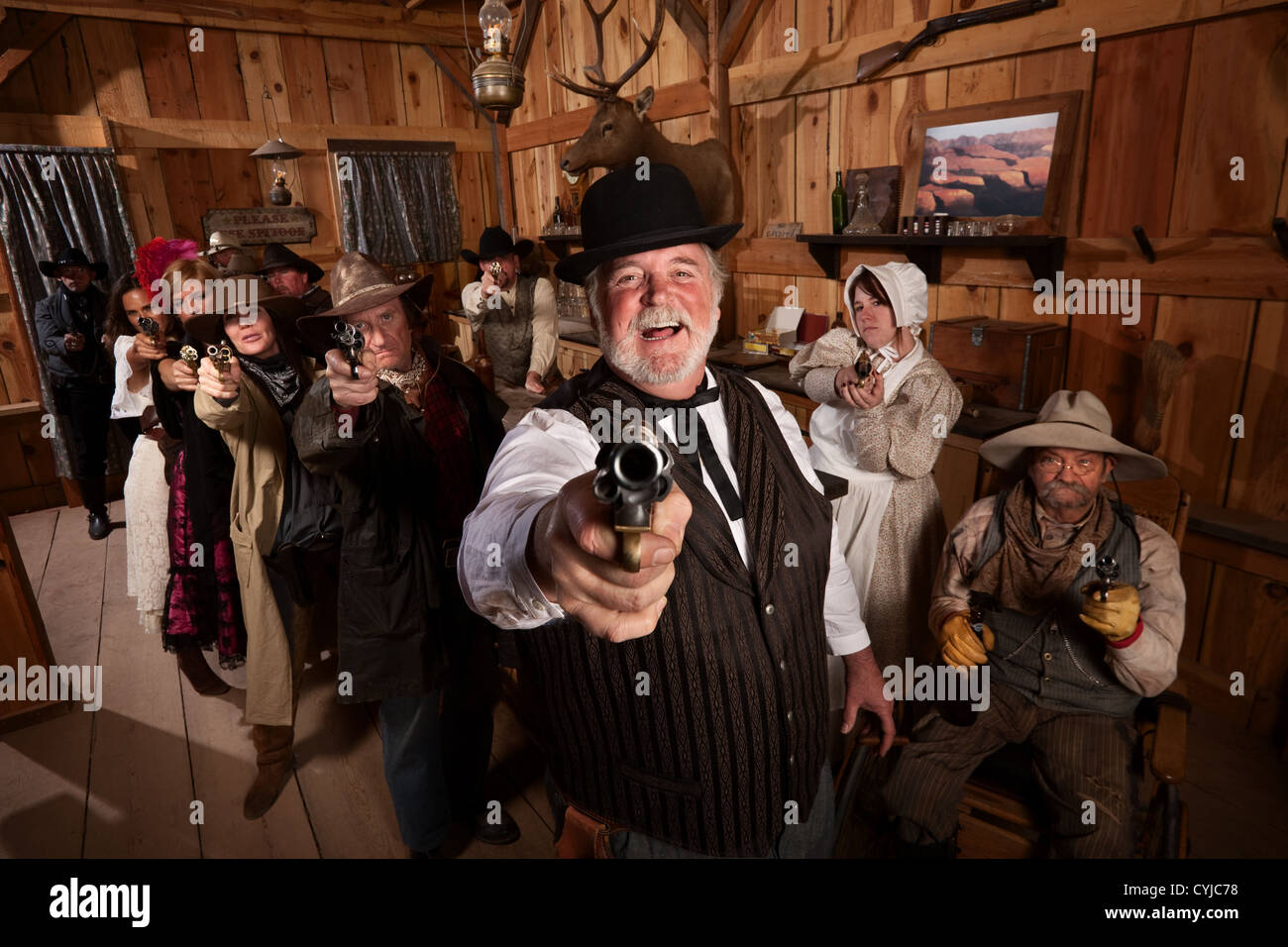 Laughing man with old west gang point guns in a saloon Stock Photo - Alamy