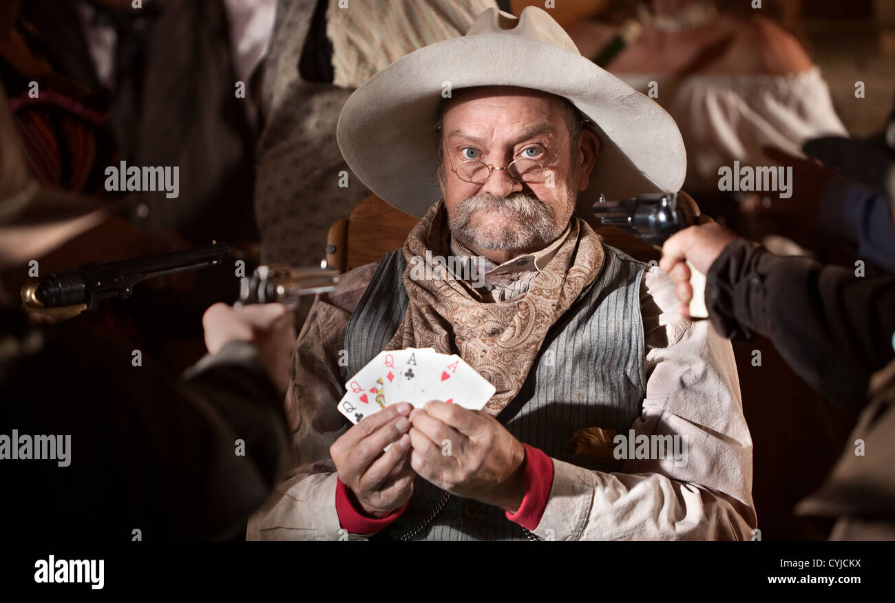 Gambler with cards and players guns pointed at him Stock Photo - Alamy