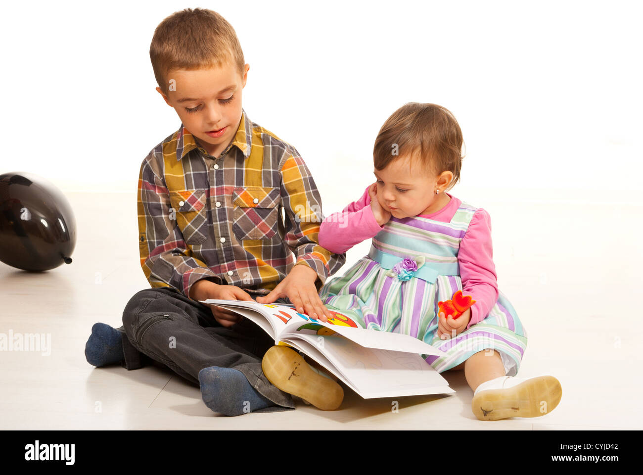 Brother teaching his little sister and showing from a book Stock Photo ...
