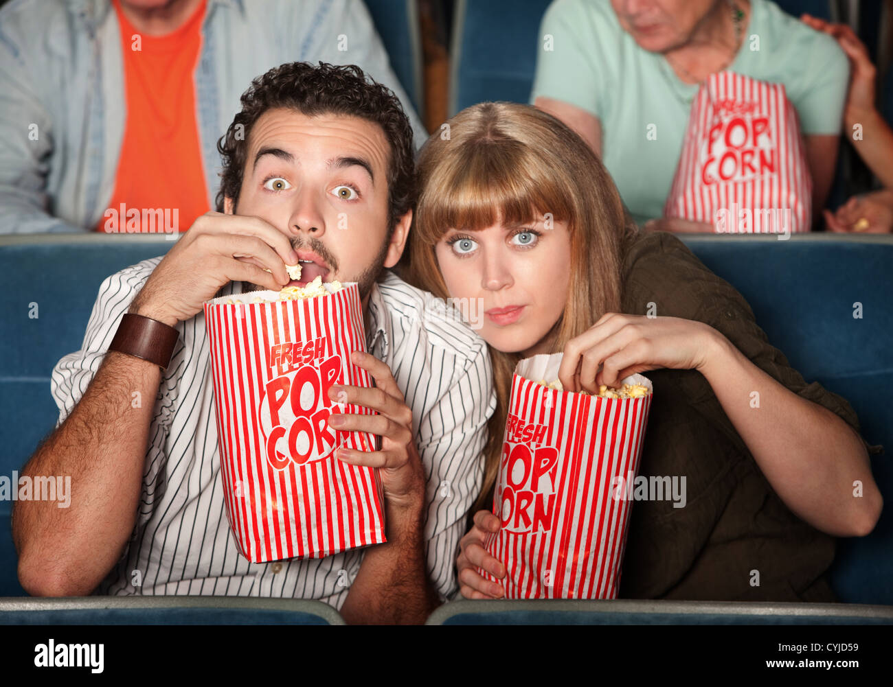 Captivated couple with popcorn bags in a theater Stock Photo - Alamy