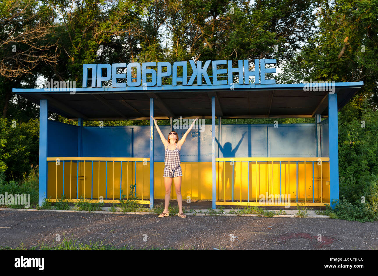Cheerful young woman at the bus stop at sunset Stock Photo - Alamy