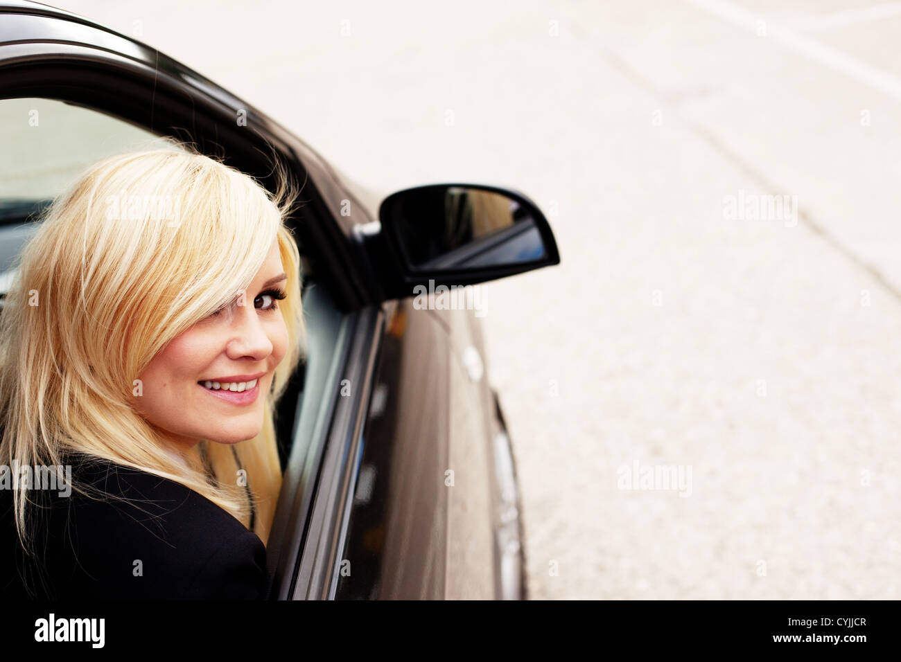 gorgeous blonde looking behind her back while driving Stock Photo - Alamy