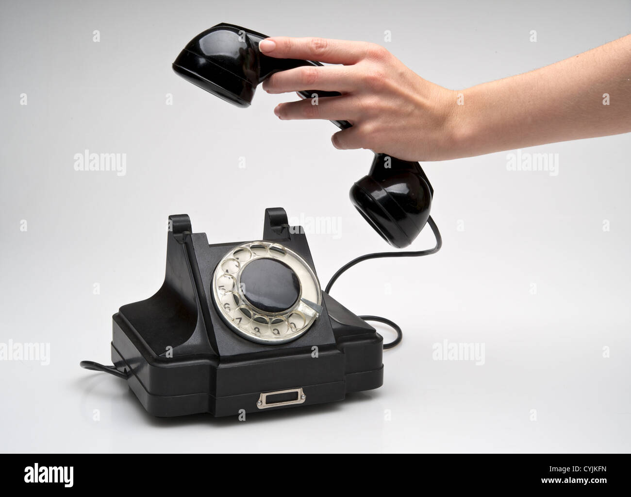 woman hand hanging up the handset of an old black telephone isolated ...