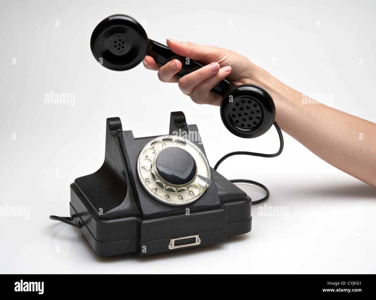 woman hand hanging up the handset of an old black telephone isolated ...