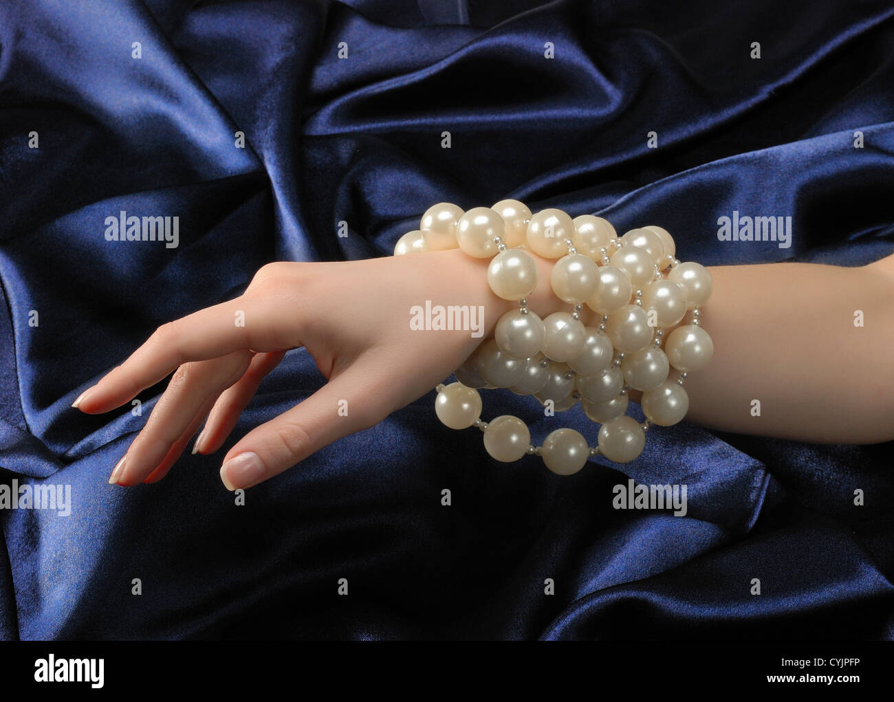 Woman's hand wearing perls necklace on blue silky background Stock ...