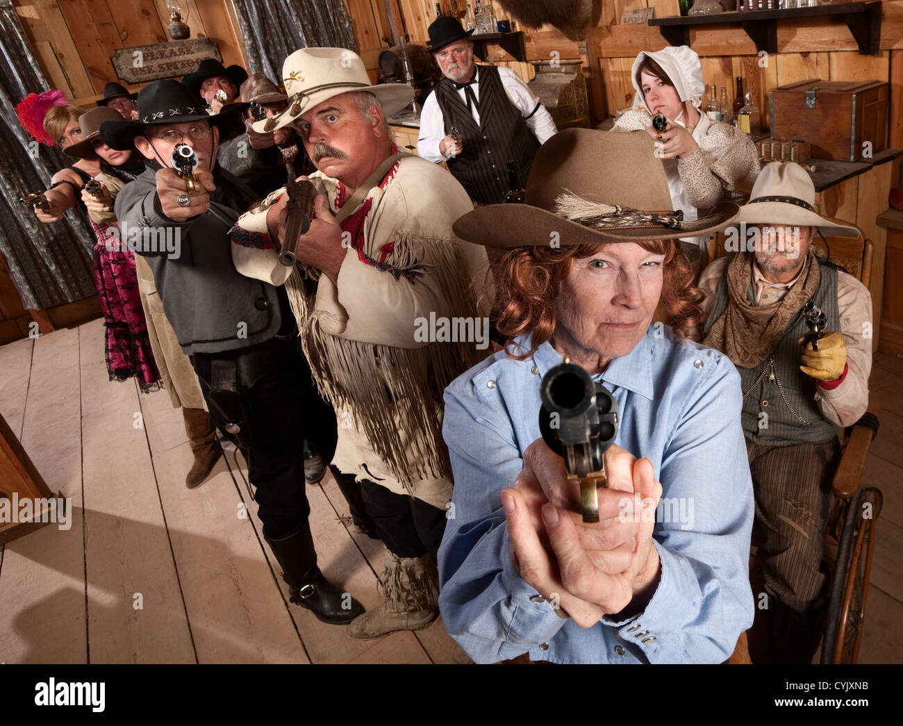 Armed senior woman and crowd points guns in old saloon Stock Photo - Alamy