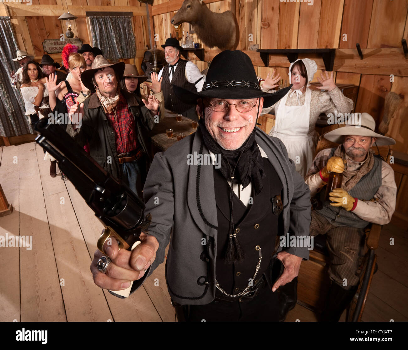 Smiling armed sheriff and group of people with hands up in saloon Stock ...