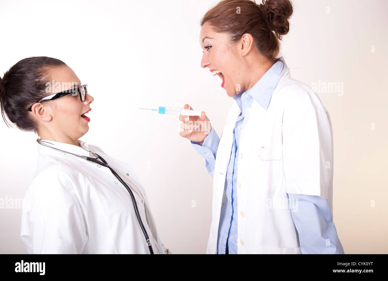 Portrait of a two young beautiful female doctors playing with syringe ...