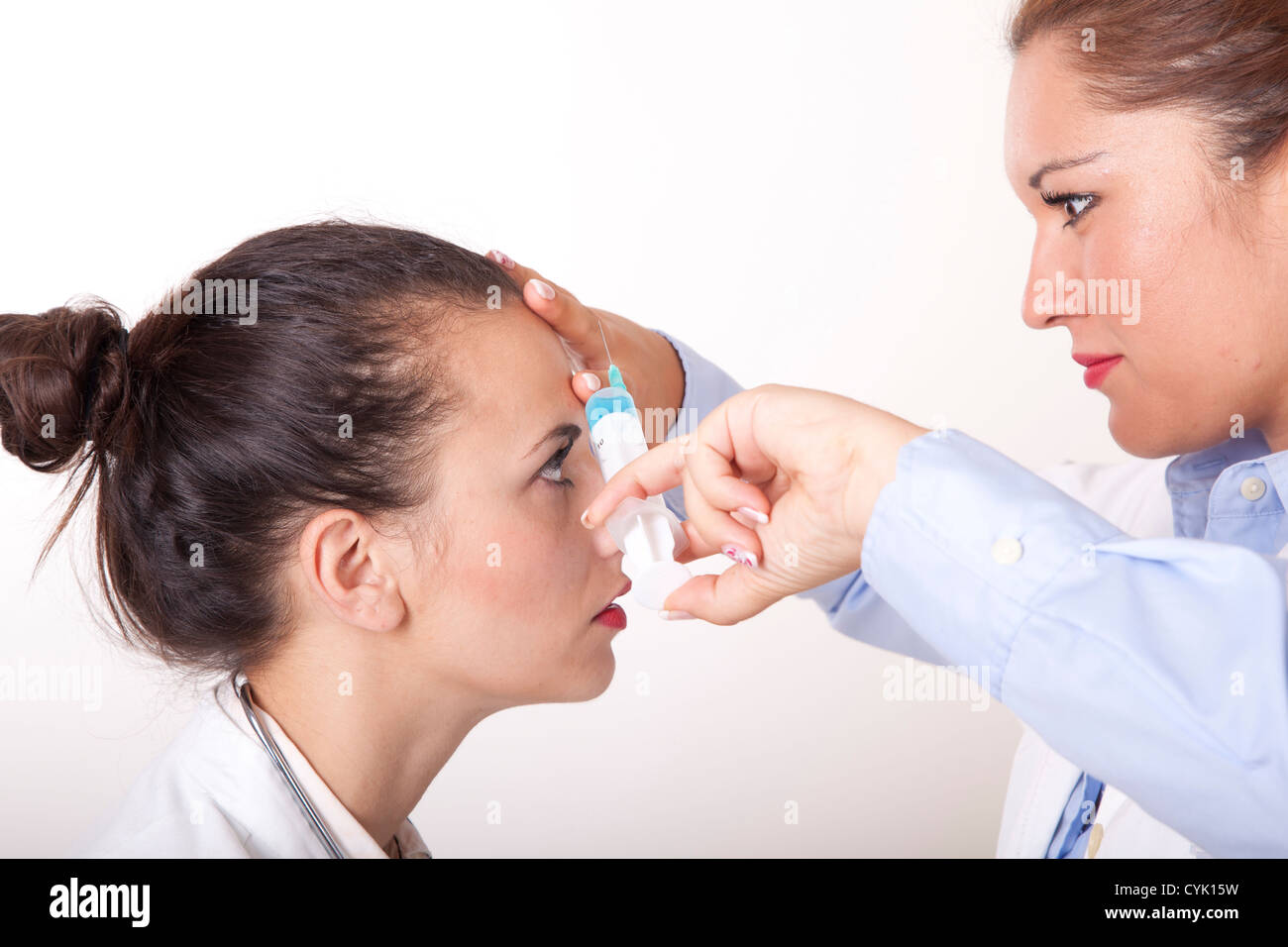 Portrait of a two young beautiful female doctors holding botox syringe ...