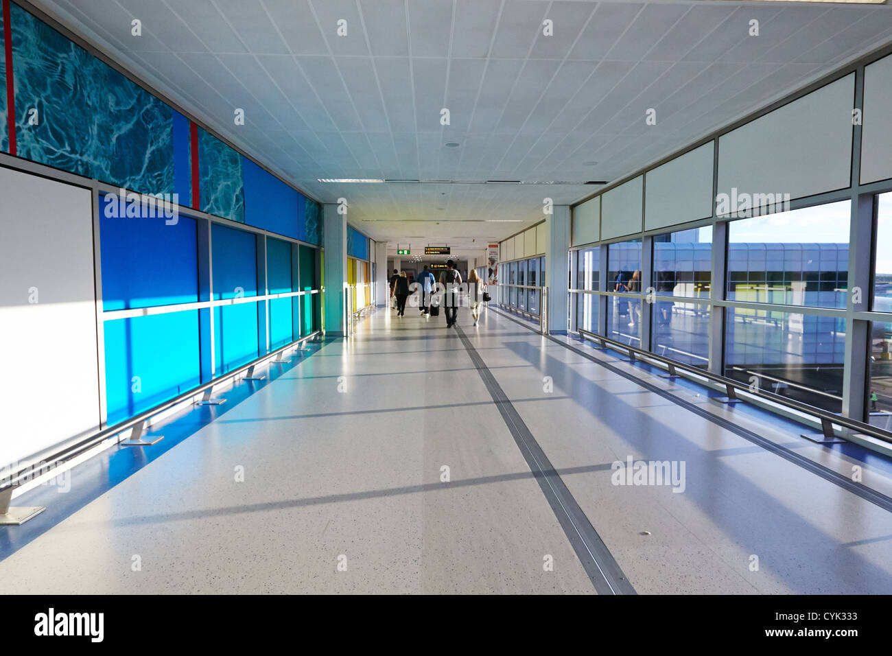 Passengers walk down a long corridor toward a boarding gate in north ...