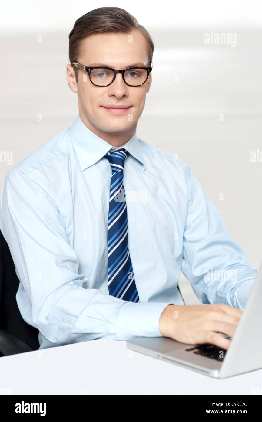 Man sitting on chair using laptop in office. Smiling at camera Stock ...