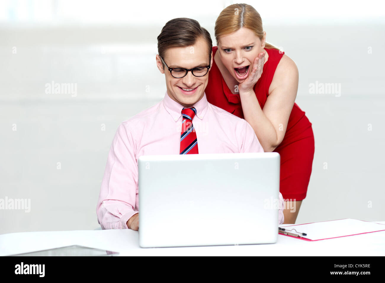 Shocked woman looking into laptop. Man working and smiling Stock Photo ...