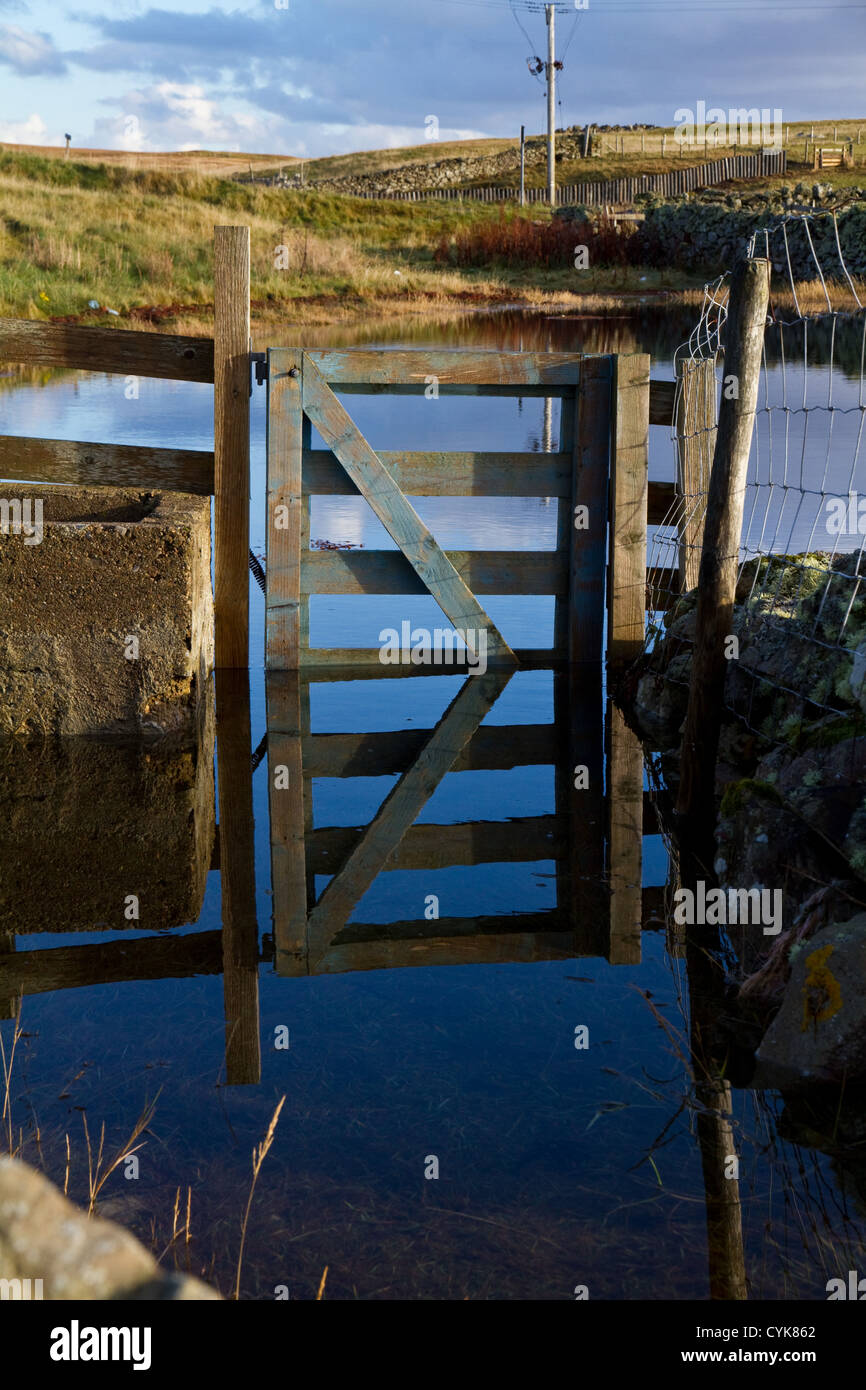 A coastal walk footpath leads through a half-submerged gate, impassable ...