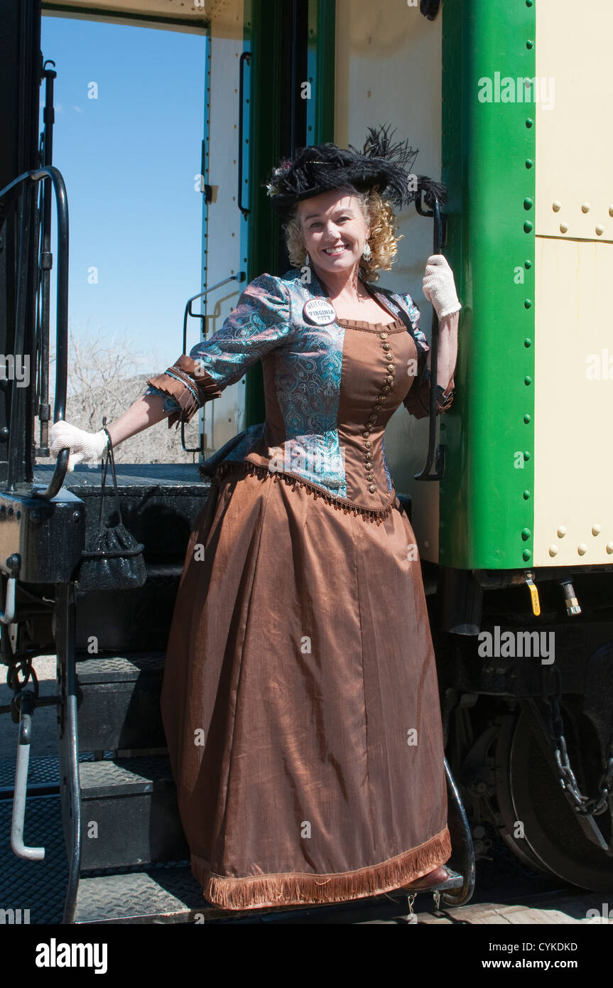 USA, Nevada. Woman in period dress beside an old steam locomotive at ...