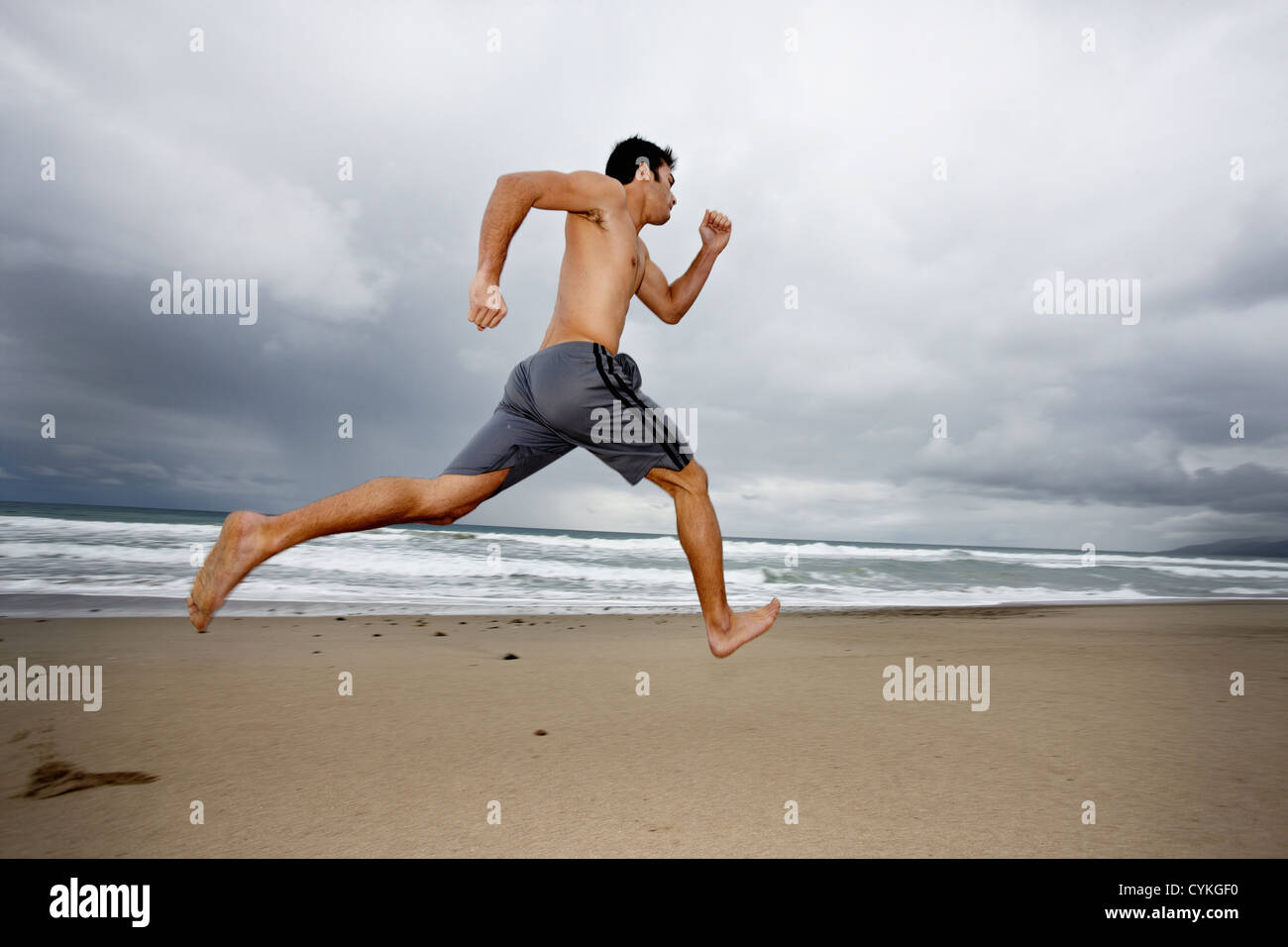 Young man running on beach Stock Photo - Alamy