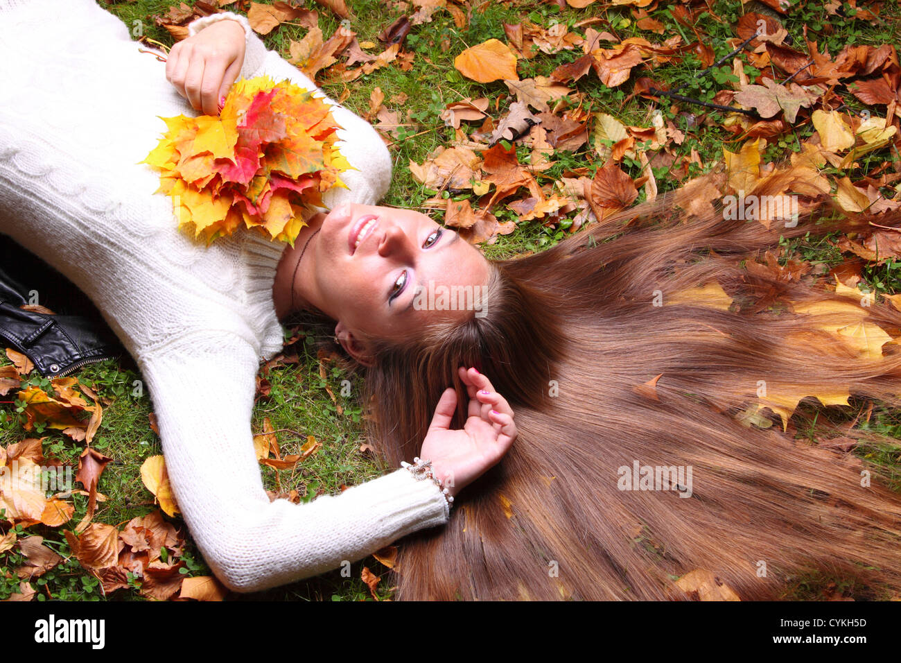 Young woman with autumn leaves in hand and fall yellow maple garden ...