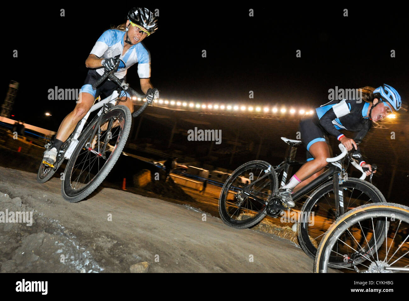 female bicycle racers on a cyclocross course at night in a stadium ...