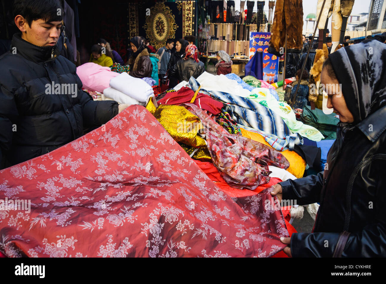 Uyghur women shopping for colorful fabrics at the bazaar in Turpan ...
