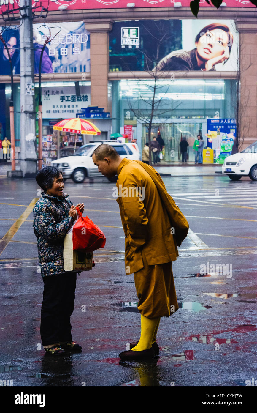 Old Chinese lady showing respect to a Buddhist monk by a shopping mall ...