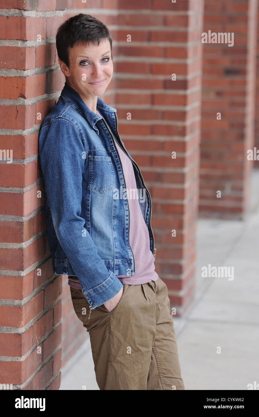 Woman leaning against brick wall Stock Photo - Alamy