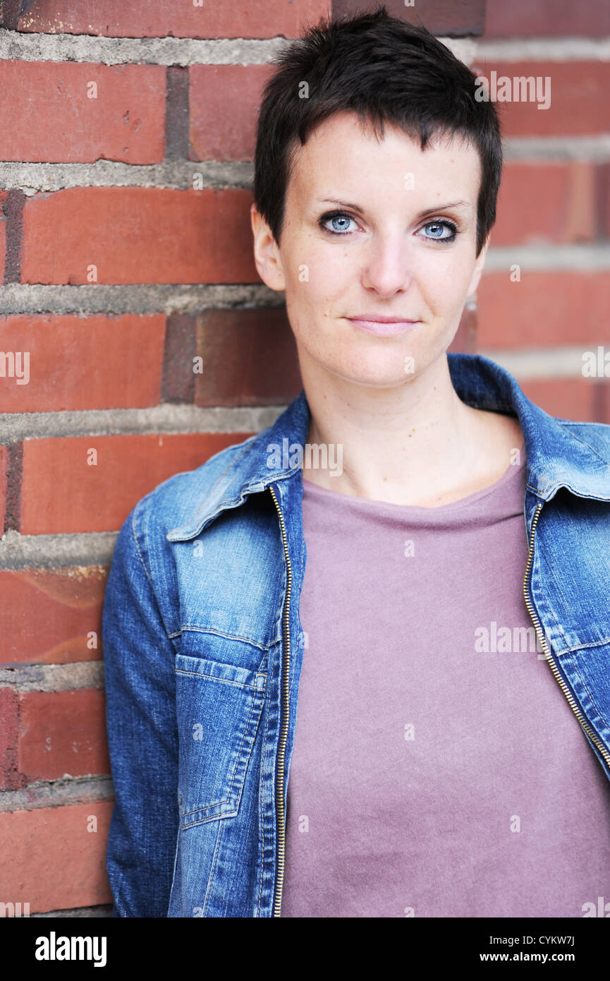 Woman leaning against brick wall Stock Photo - Alamy
